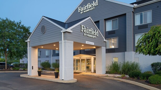 Um hotel Fairfield by Marriott com entrada coberta, sinalização clara e um acesso por uma alameda arborizada.