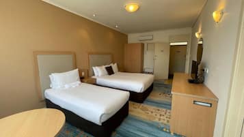 Quarto de hotel com duas camas, uma escrivaninha e um espelho.