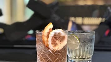 Duas bebidas geladas, uma com uma fatia de laranja e outra com uma fatia de limão, sobre uma mesa.