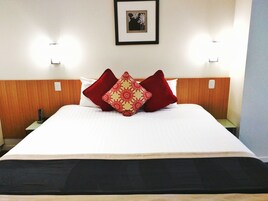 Quarto de hotel com uma cama, duas mesas de cabeceira e um quadro pendurado na parede.