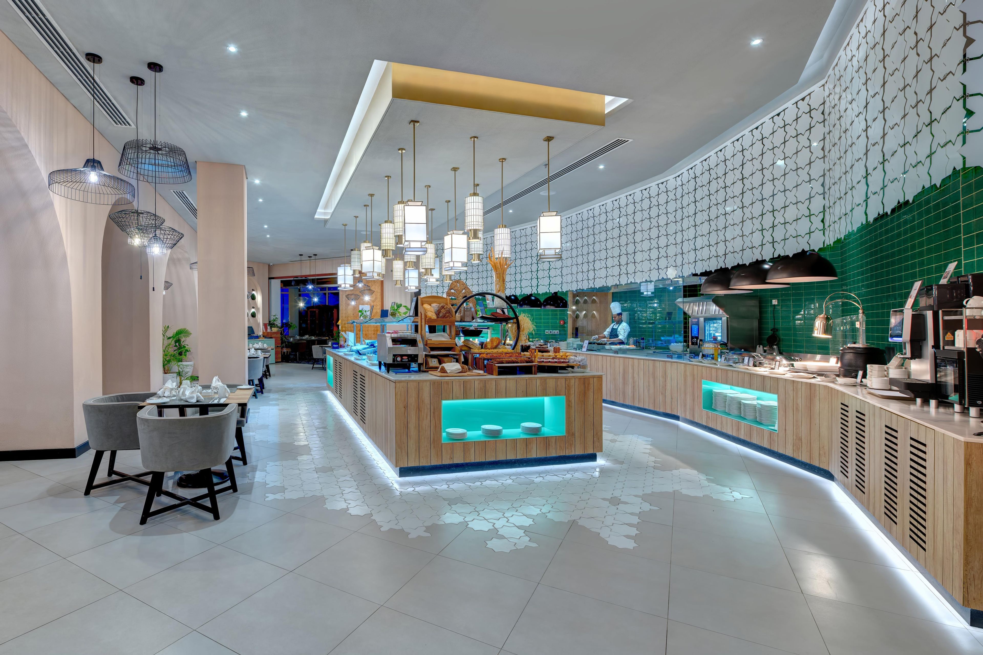 Um lobby moderno de hotel com balcão de recepção central, área de estar e iluminação decorativa.