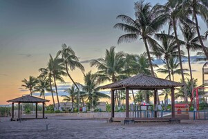 Na praia, areia branca, guarda-sóis, toalhas de praia 
