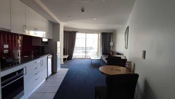 Quarto de hotel moderno com cozinha, área de refeições e varanda com vista.