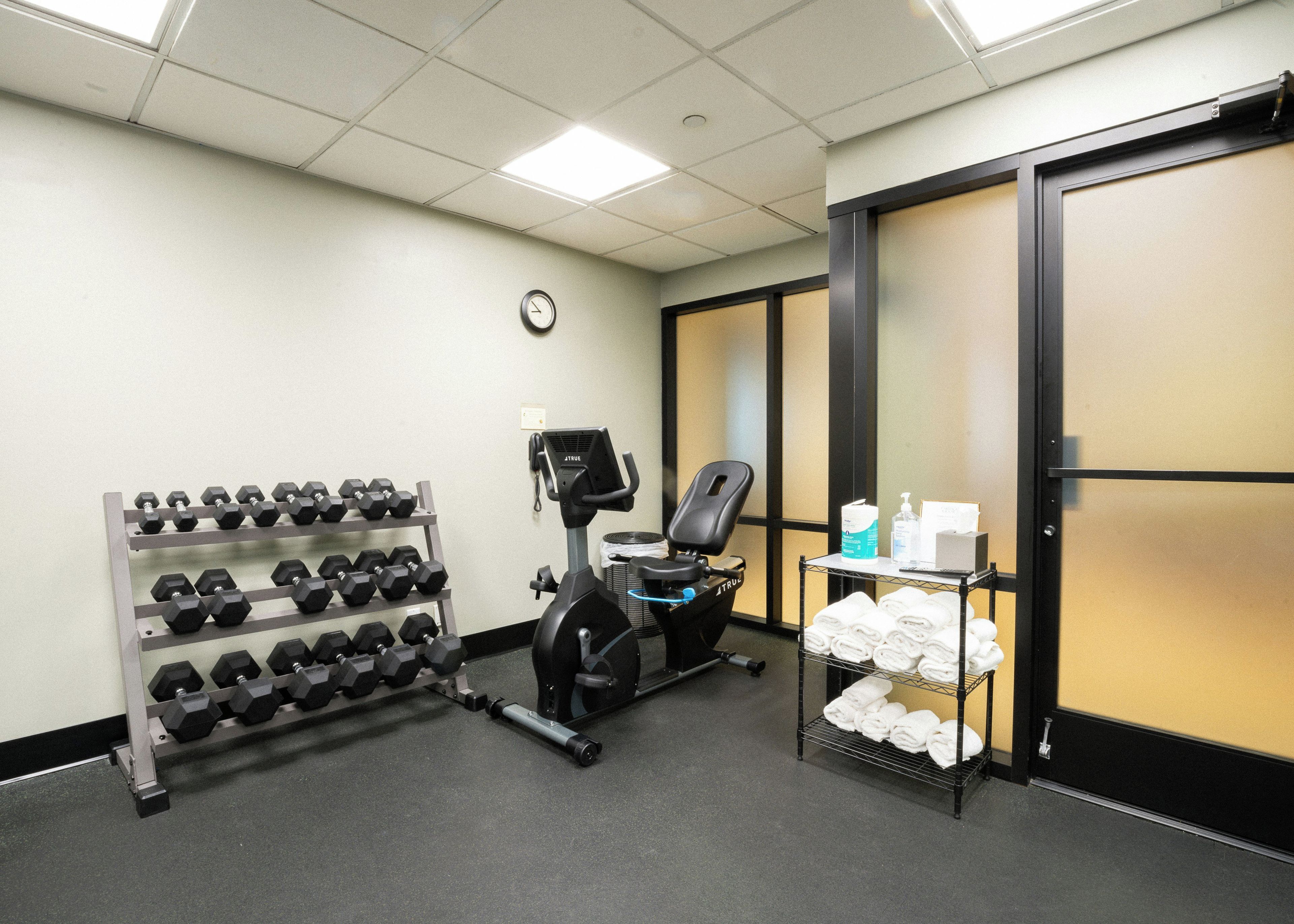 Uma academia com equipamentos de exercício, toalhas e um relógio na parede.