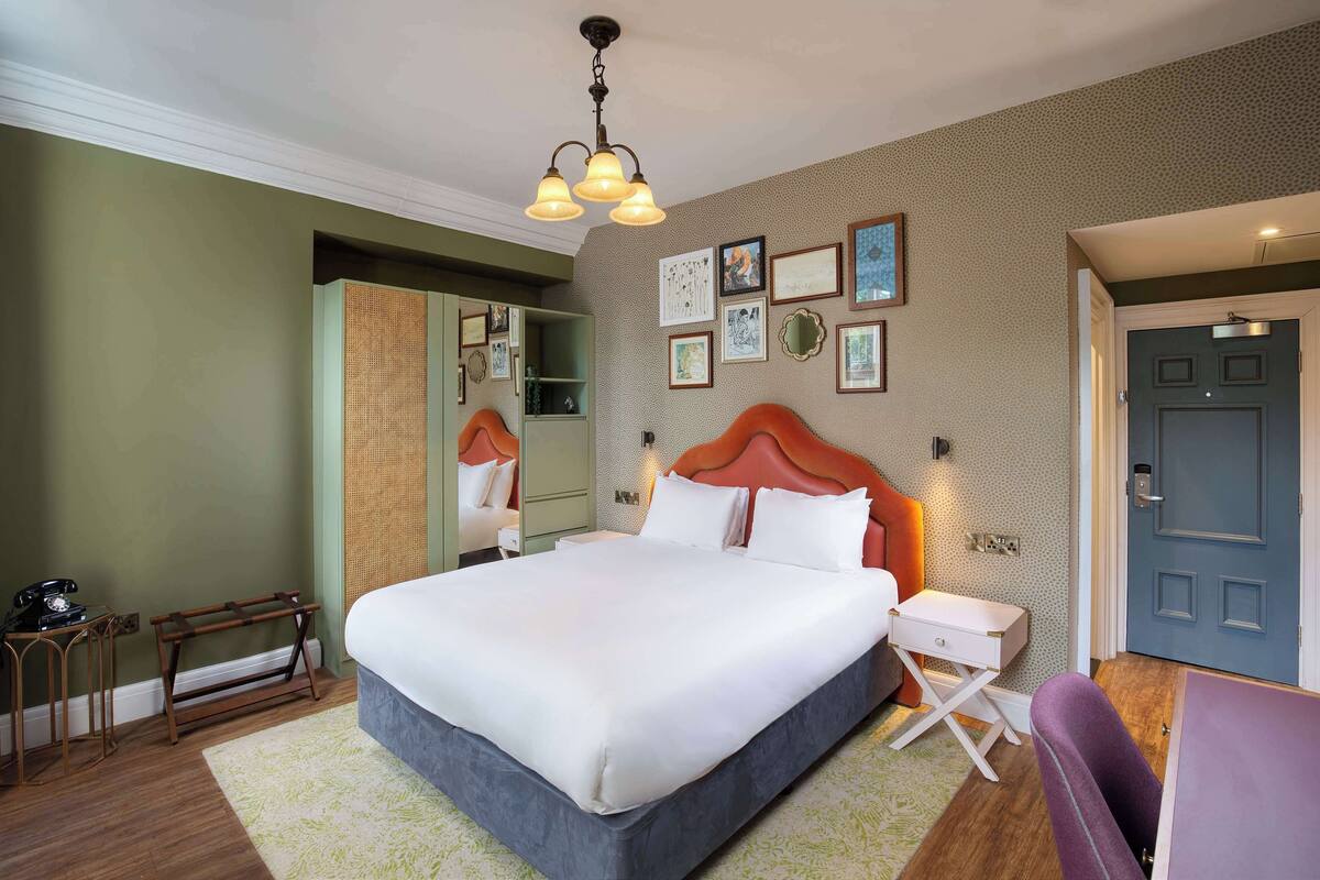Quarto bem arrumado com uma cama grande, mesas de cabeceira, um guarda-roupa e uma porta.