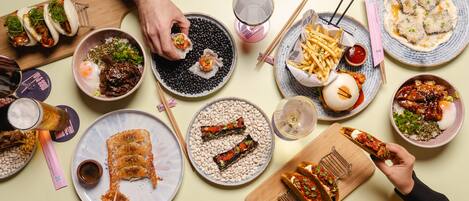 Diversos pratos em chapas, incluindo sushi, alimentos fritos e uma tigela com ovo frito.