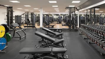 Uma academia com diversos equipamentos de exercício, incluindo bancos e halteres.