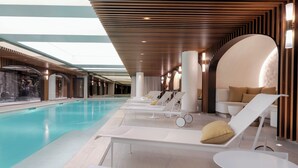 Uma área interna moderna com piscina, cadeiras de descanso e um espaço para sentar.