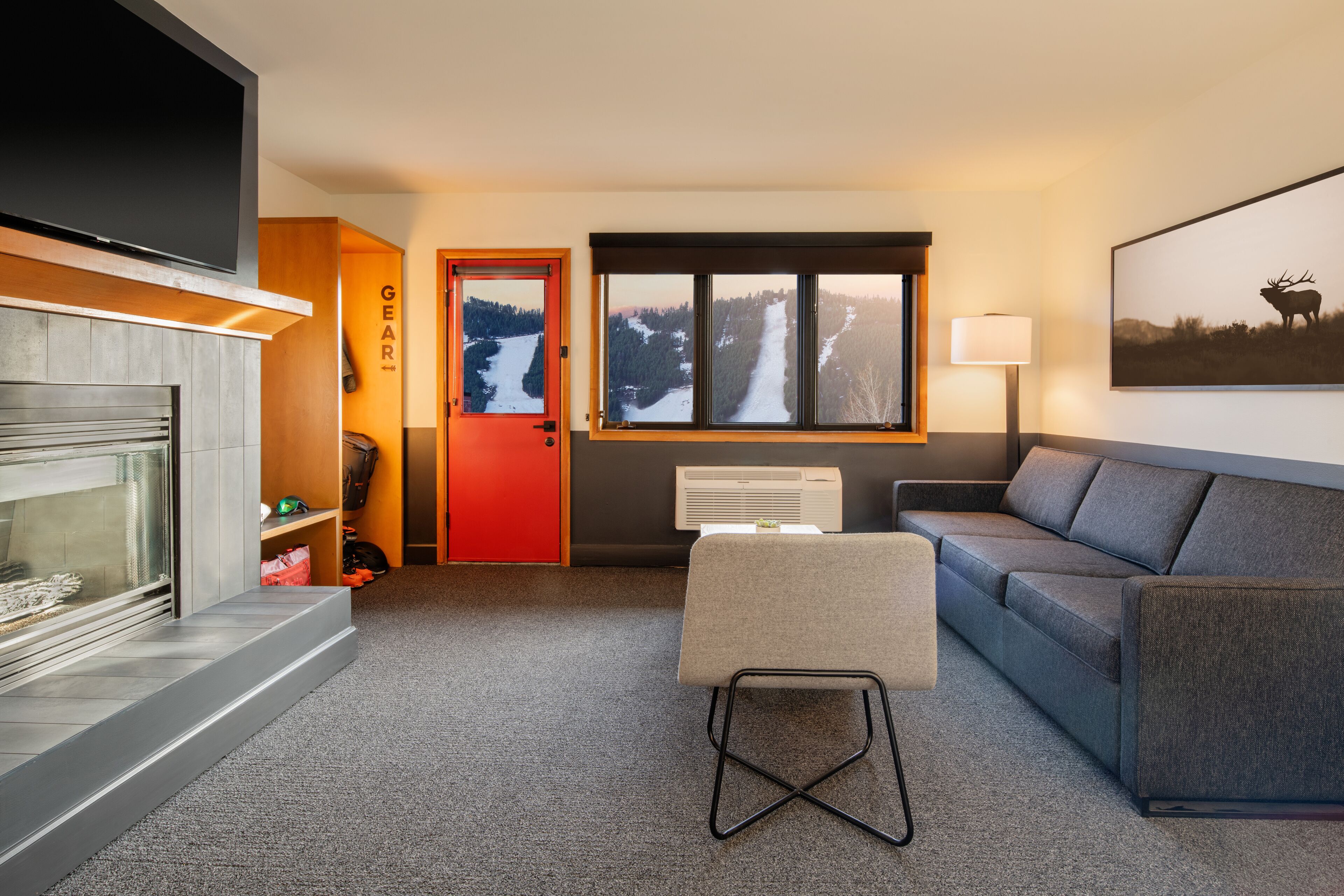 Uma sala de estar moderna com lareira, sofá, TV e janela com vista para a neve.