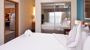 Quarto de hotel com cama grande, banheiro privativo, cozinha compacta e televisão.