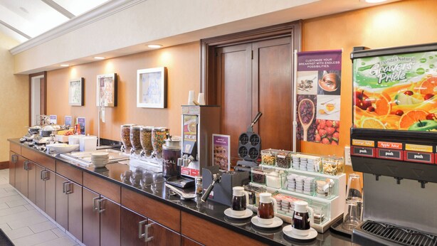 Um balcão de buffet com diversos alimentos, uma máquina de café e um dispensador de bebidas.