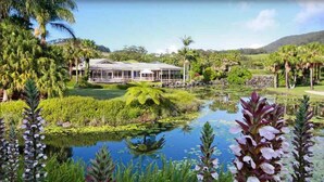 Um resort com um edifício grande, um lago e vegetação exuberante.