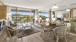 Uma sala de estar ampla com varanda, móveis de vime e uma mesa de jantar com cadeiras.