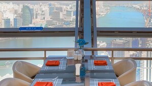 Uma mesa com vista para a cidade, um jogo americano, um vaso com uma flor azul e uma placa indicando a Ponte Yangpu.