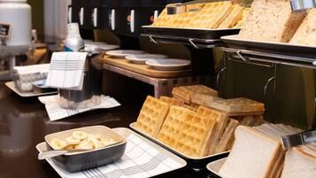 Buffet com waffles, sanduíches e uma tigela de bananas fatiadas.