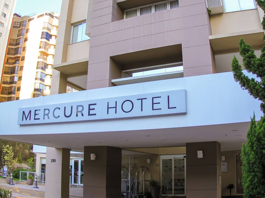Exterior do Hotel Mercure com fachada moderna, entrada destacada e céu claro.
