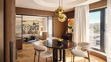 Uma sala de estar moderna com uma mesa de jantar redonda, duas cadeiras, um sofá e uma janela grande com cortinas.