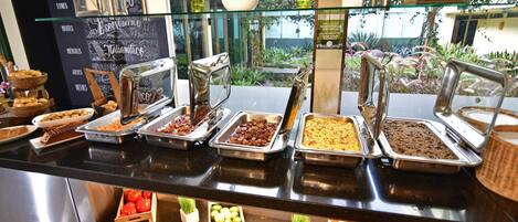 Buffet com diversas opções de comida e vista para o jardim.