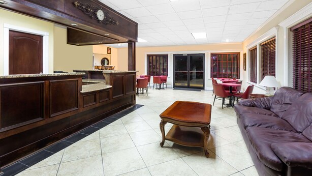 Uma sala de estar ampla com um balcão em madeira escura, um sofá de couro e uma mesa de jantar com cadeiras.