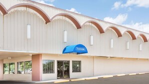 Um hotel Travelodge com fachada branca, janelas em arco e toldo azul.
