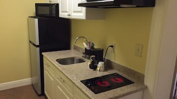 Uma cozinha compacta equipada com micro-ondas, frigorífico, pia e fogão.