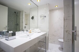 Uma casa de banho moderna com um espelho grande, duas pias e um chuveiro com parede de vidro.
