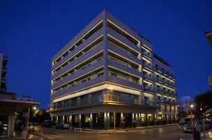 Um hotel de vários andares com design moderno, apresentando varandas em cada andar e entrada no nível da rua.