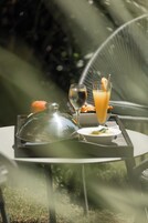 Uma mesa com um copo de suco de laranja, uma taça de vinho e um recipiente com alimento.