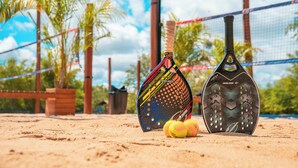 Uma quadra de voleibol de praia, com duas bolas e duas raquetes.