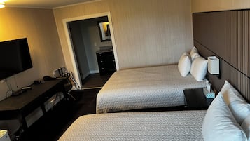 Quarto de hotel com duas camas, televisão, escrivaninha e espelho.
