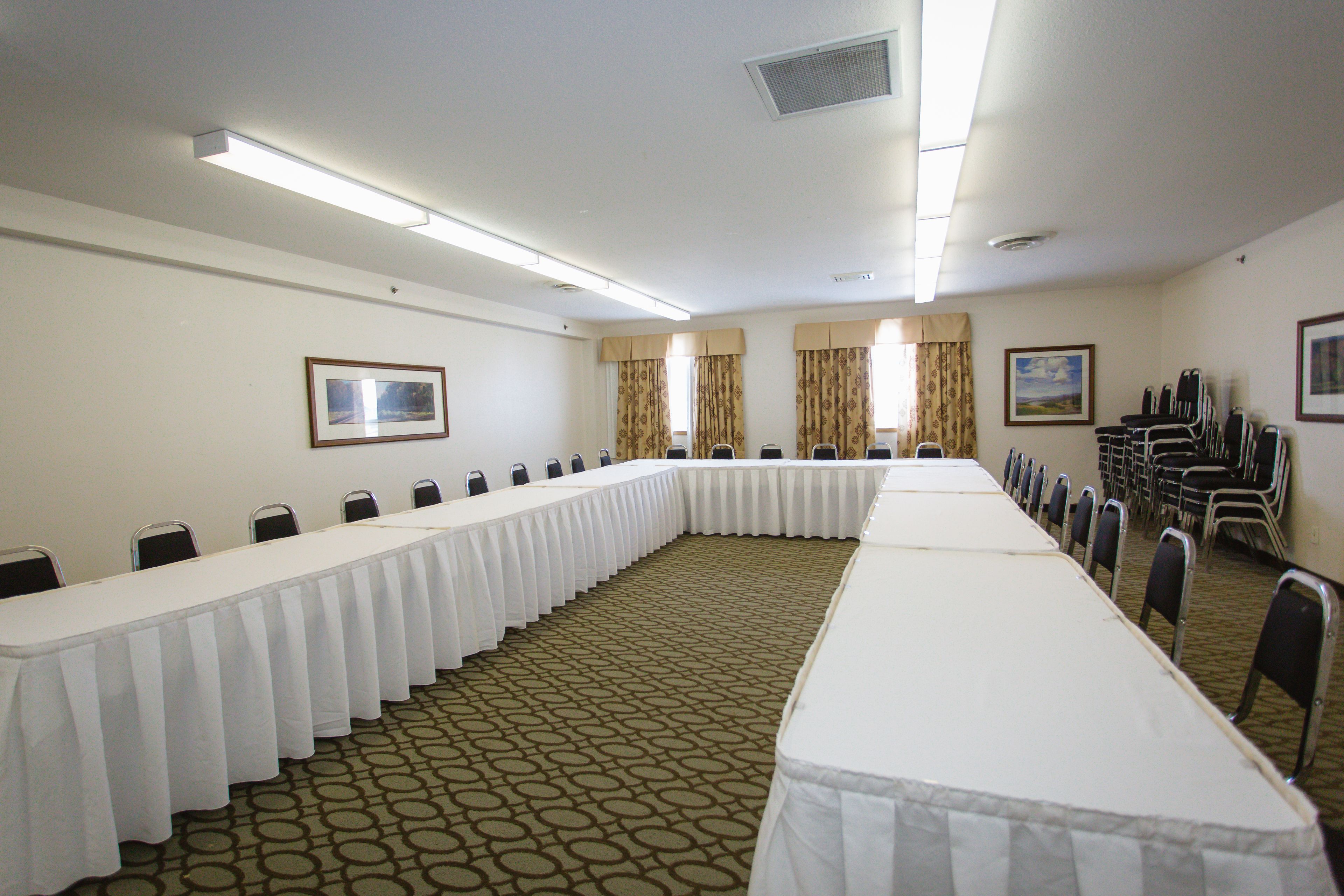 Uma sala de conferências com uma mesa comprida, cadeiras e piso coberto de carpete.