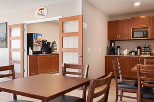 Quarto de hotel com bancada de café da manhã, micro-ondas e máquina de café.
