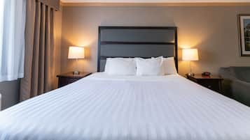 Quarto de hotel com uma cama grande, duas mesas de cabeceira com luminárias, uma cabeceira e um quadro na parede.