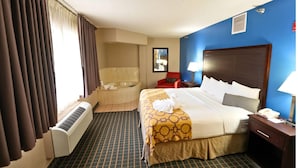 Quarto de hotel com cama grande, banheira integrada, escrivaninha e uma cadeira.