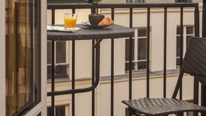 Uma varanda com uma mesa posta para o café da manhã, incluindo um copo de suco de laranja e um croissant.
