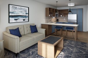 Uma sala de estar moderna com um sofá, uma mesa de centro e uma área de cozinha com mesa de jantar.