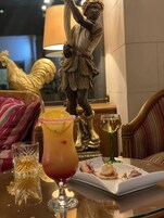 Uma mesa de jantar com um coquetel, uma taça de vinho e um prato de comida.