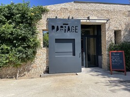 Entrada de um edifício com fachada de pedra e uma placa com a inscrição 'PARTAGE'.