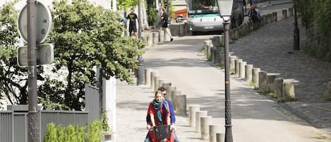 Uma rua de paralelepípedos com um ciclista, um ônibus e pedestres.