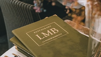 Uma pilha de cardápios verdes com o texto "RESTAURANT LMB LA MAISON BARROTTE" sobre uma mesa.