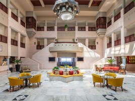 Um hall amplo com área de estar central, várias varandas e um lustre decorativo.