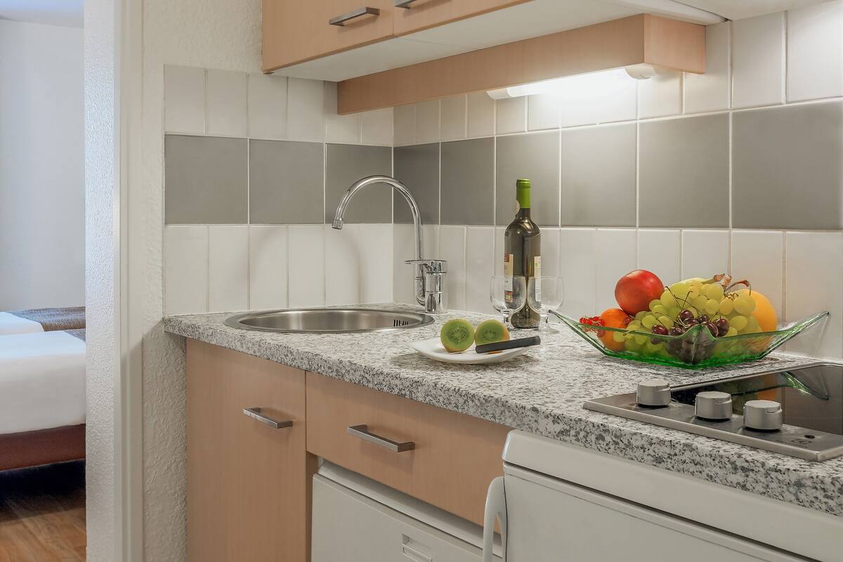 Cozinha moderna com bancada de granito, pia de aço inoxidável e uma fruteira.