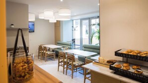 Uma sala de jantar moderna com mesas, cadeiras e um balcão com pastelaria.