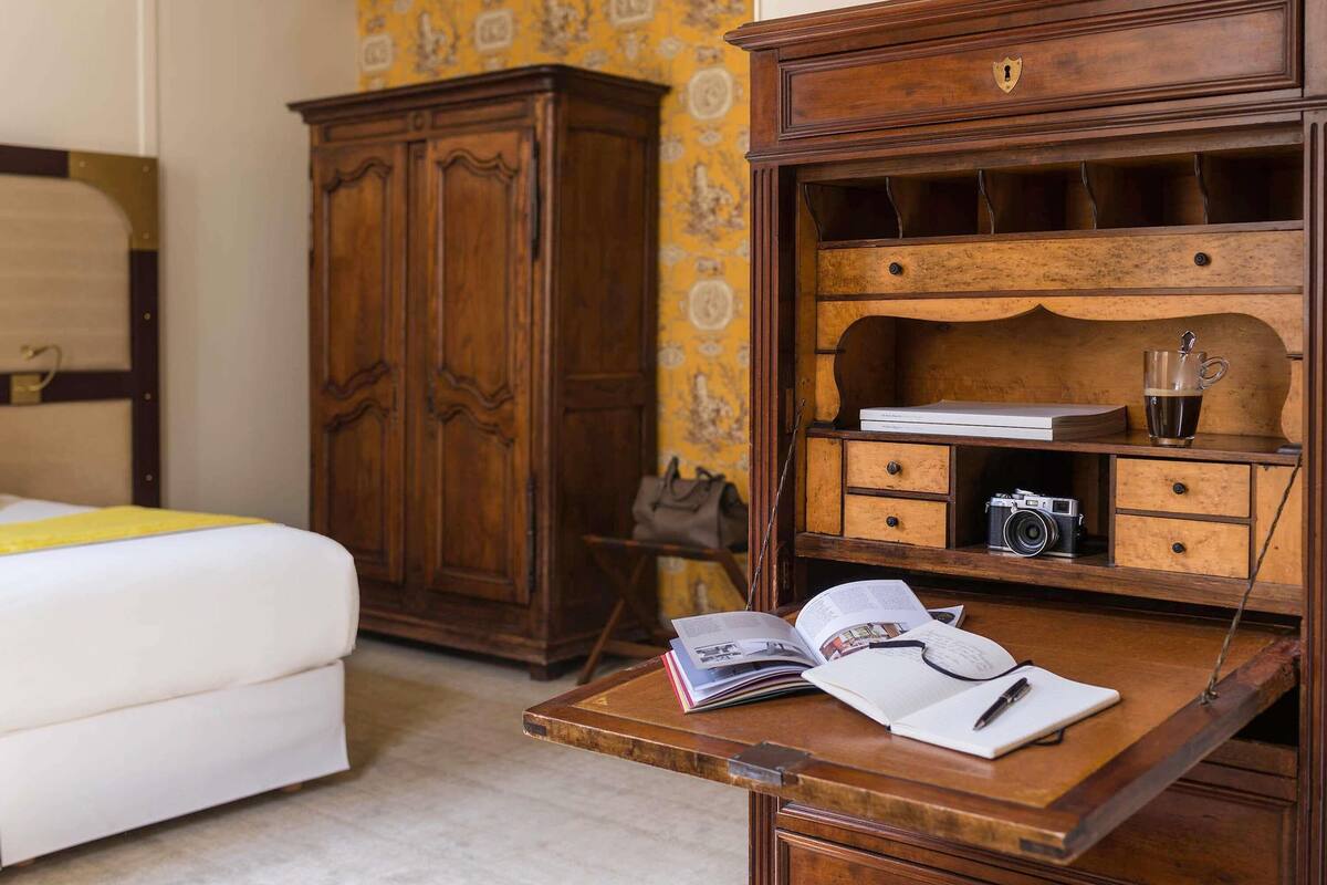 Quarto com escrivaninha de madeira, uma cama e um guarda-roupa.