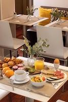 Uma mesa posta para o café da manhã com croissants, frutas, ovos e suco.
