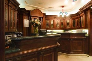 Cozinha tradicional com armários de madeira, bancada de mármore e lustre.