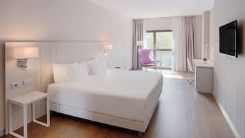 Quarto de hotel moderno com uma cama grande, mesas de cabeceira, uma escrivaninha e uma televisão.
