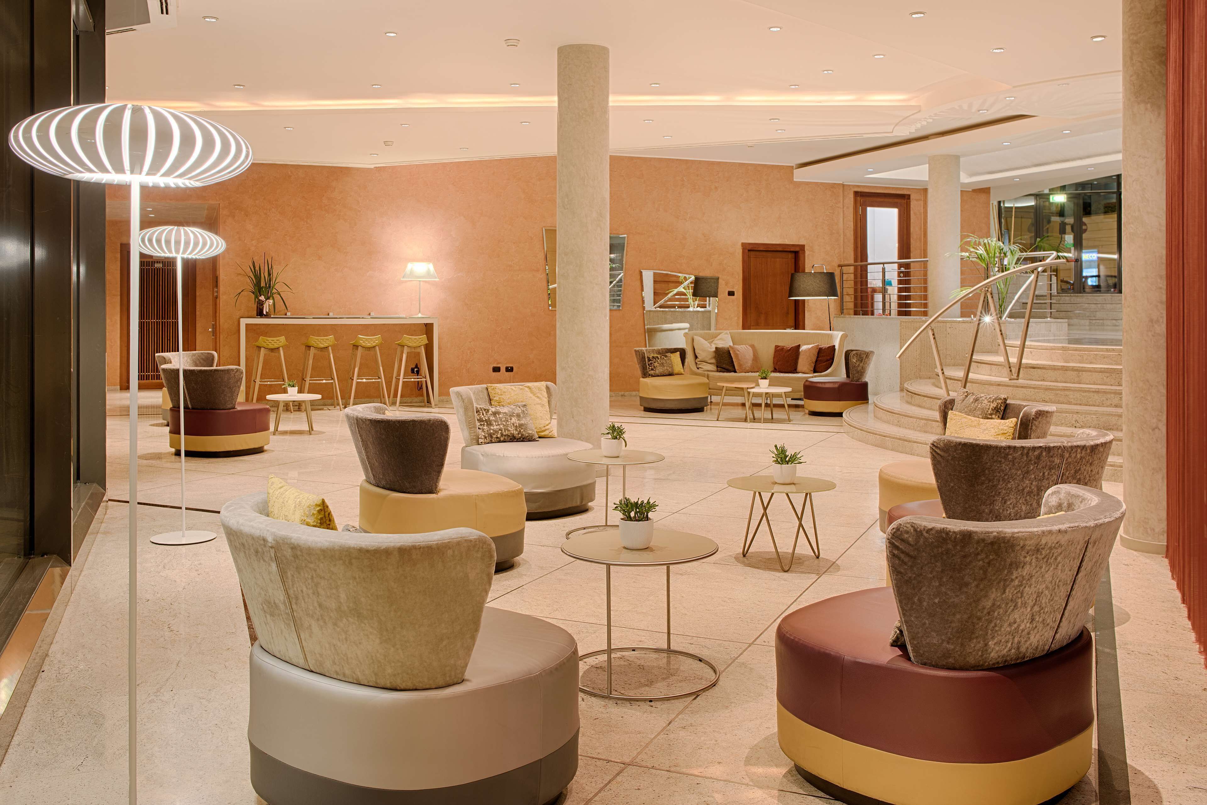 Um lobby moderno com assentos arredondados, uma mesa de recepção e uma escadaria.