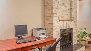 Escritório em casa com escrivaninha, computador, impressora e lareira.