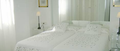 Quarto com duas camas, uma mesa de cabeceira, um abajur e um quadro na parede.